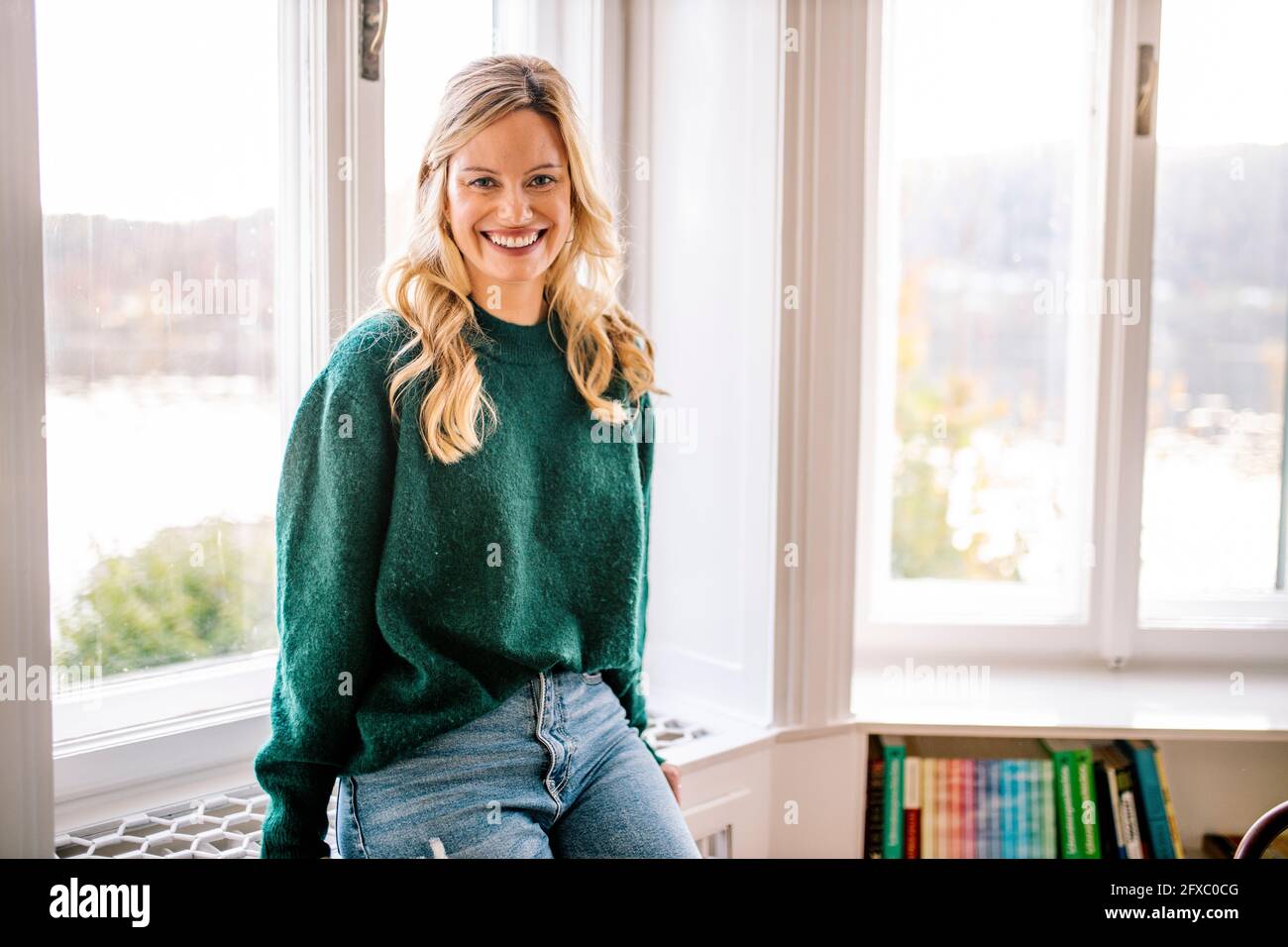 Beautiful woman leaning over window sill at office Stock Photo - Alamy