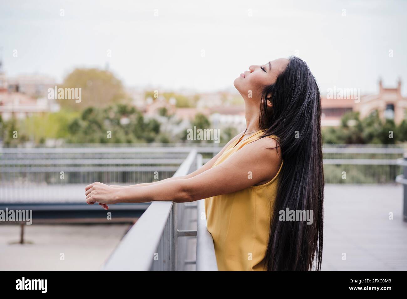 Woman standing with head back at railing on elevated walkway Stock ...