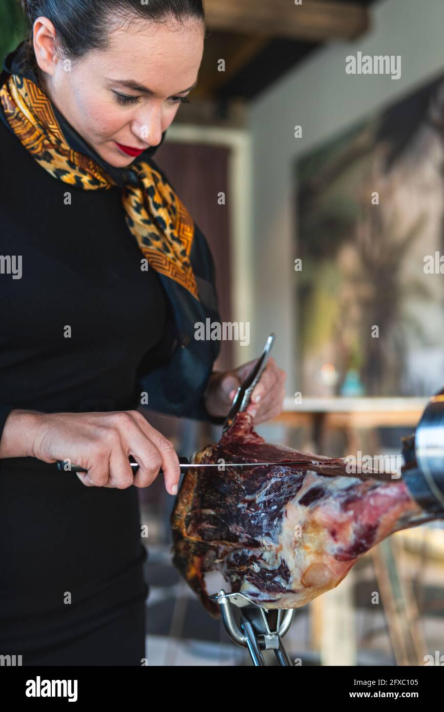 Young female chef cutting meat with knife in restaurant Stock Photo - Alamy