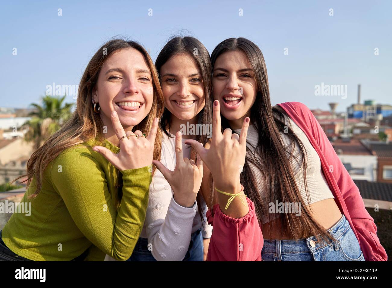 Female friends with cool attitude gesturing horn sign Stock Photo - Alamy