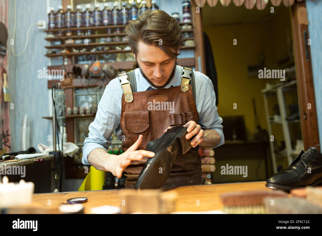 Male cobbler examining shoe at workshop Stock Photo - Alamy