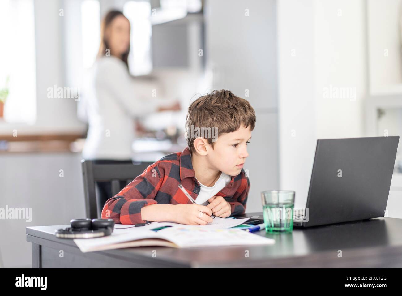 Boy concentrating whiling studying through laptop at home Stock Photo ...