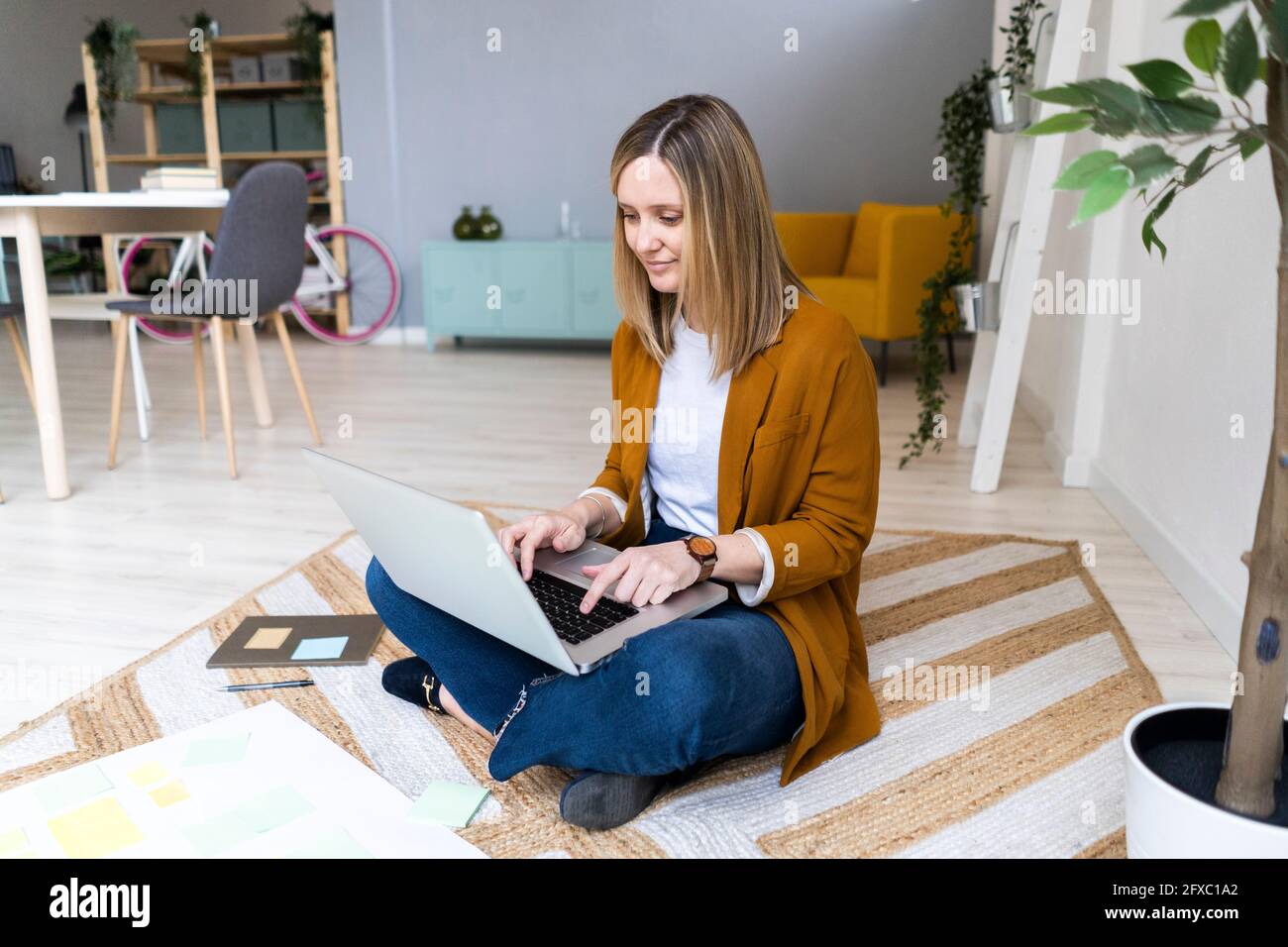 Female creative businesswoman using laptop on carpet in office Stock ...