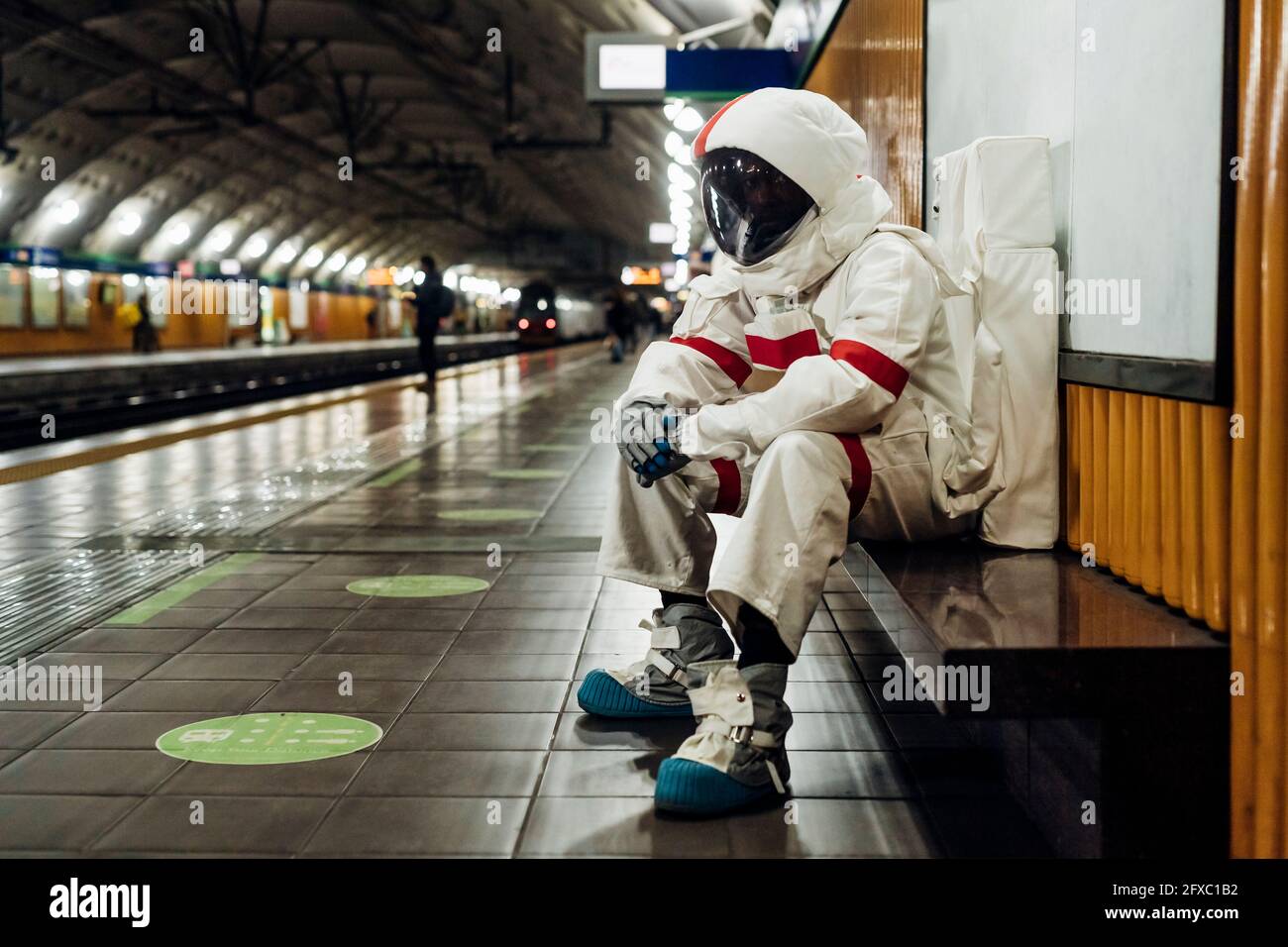 Male astronaut sitting on bench at railway platform Stock Photo - Alamy