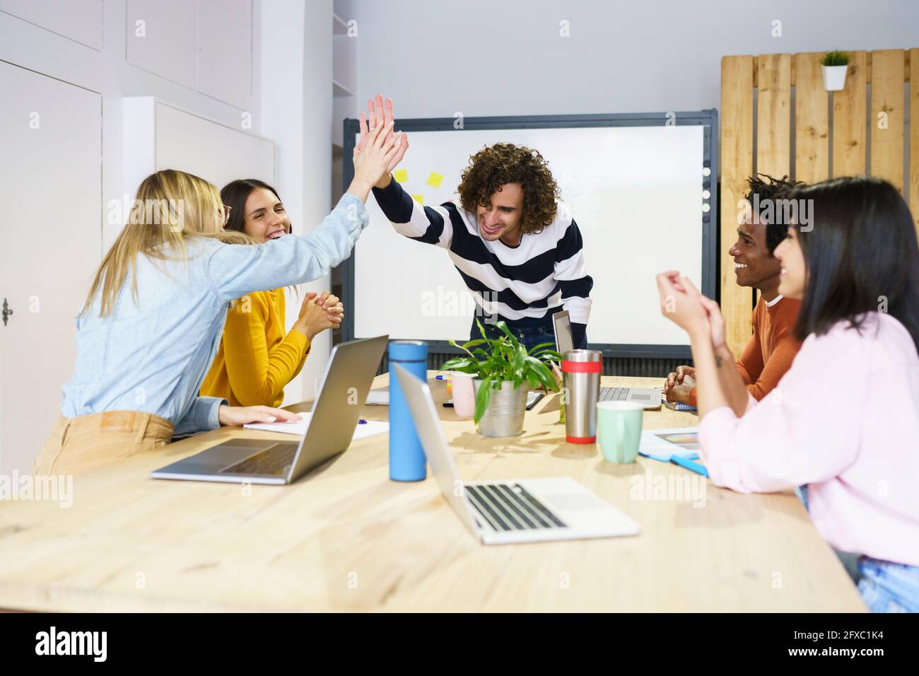 Business colleagues high-fiving at board room in office Stock Photo - Alamy
