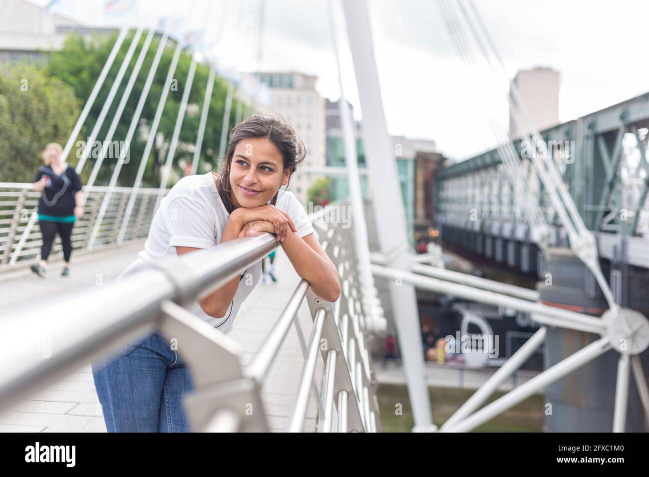 Smiling beautiful woman leaning on railing at bridge Stock Photo - Alamy
