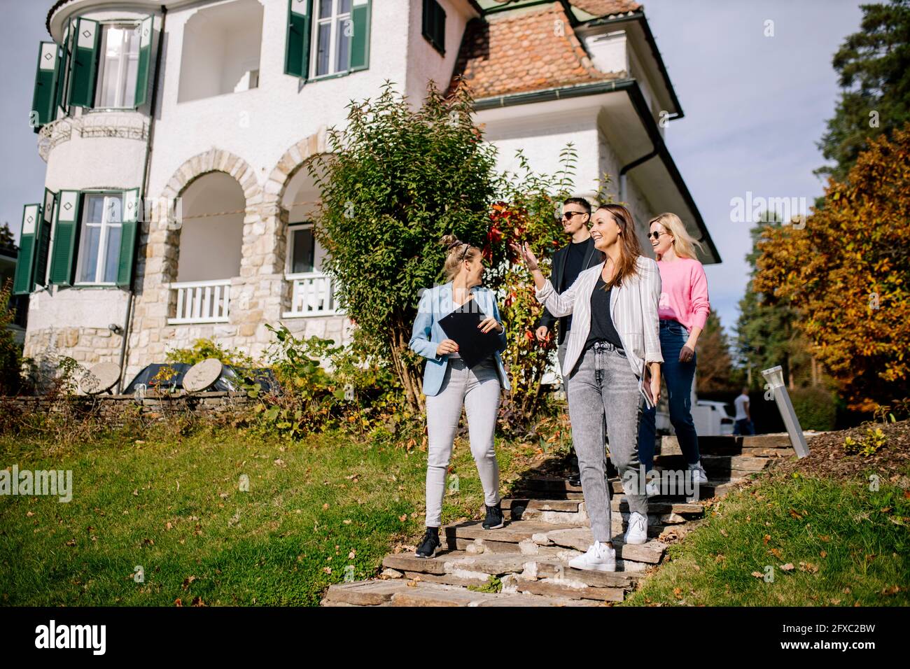 Female entrepreneurs with customers walking down steps in garden Stock ...