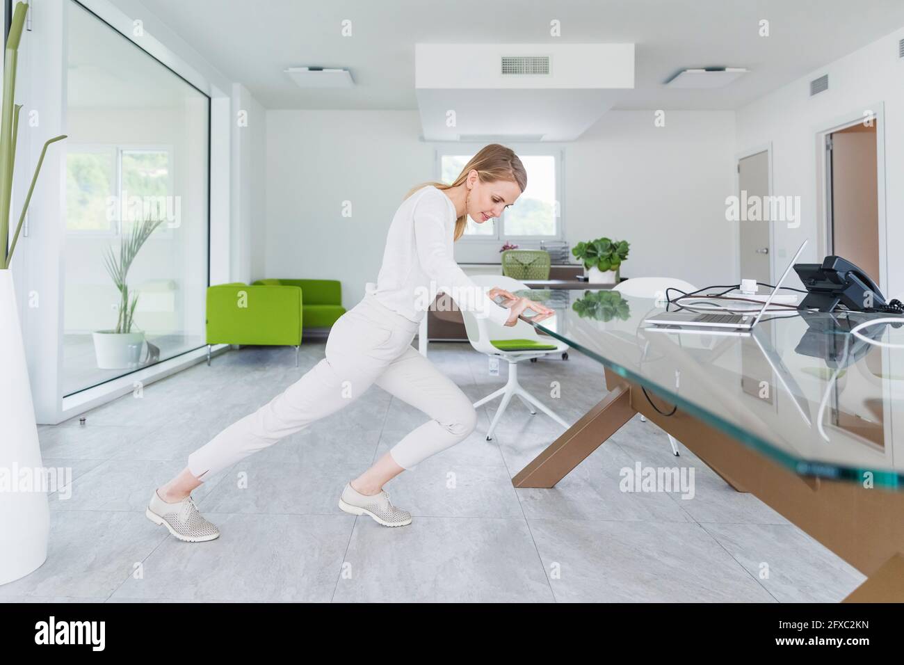 Businesswoman stretching over conference table at office Stock Photo ...