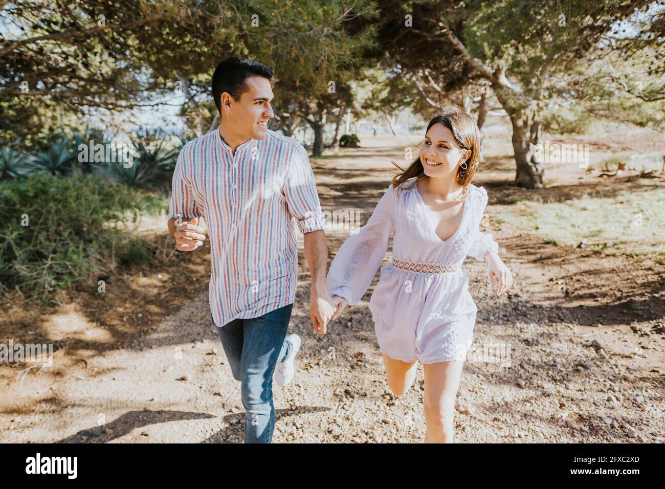 Carefree boyfriend and girlfriend holding hands while running Stock ...