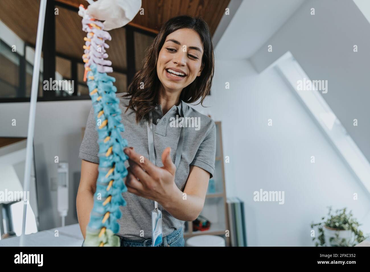 Smiling female trainer explaining spine model in classroom Stock Photo ...