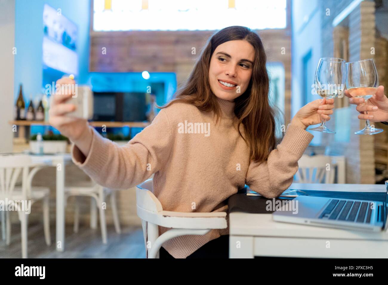 Woman taking selfie through smart phone while raising toast at ...