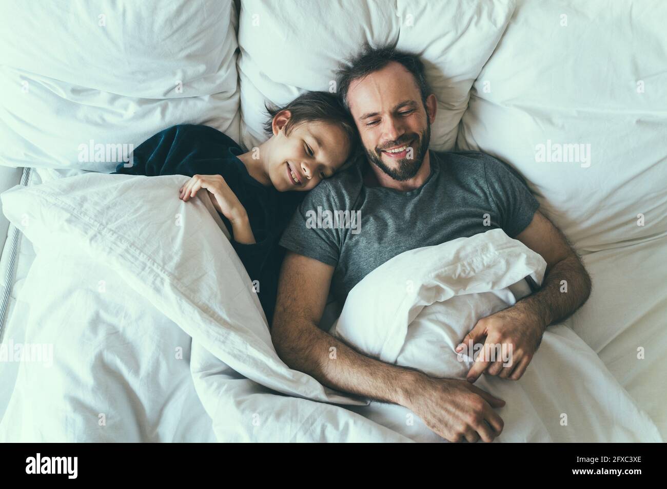 Father and son with blanket lying on bed at home Stock Photo - Alamy