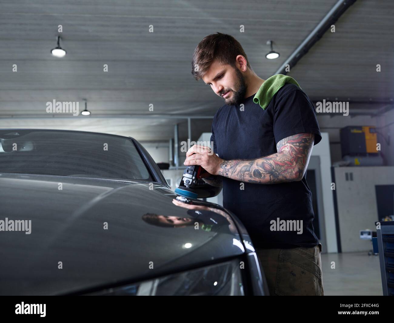 Technician polishing car with equipment at garage Stock Photo - Alamy