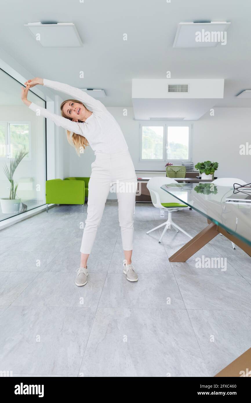 Female professional doing stretching exercise by conference table in ...