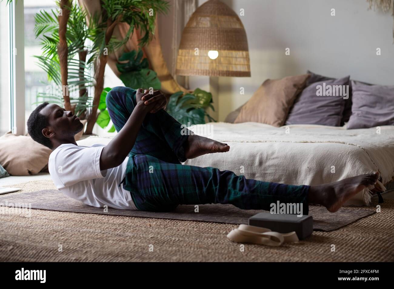 African man doing yoga on the floor, practicing the Supported One ...