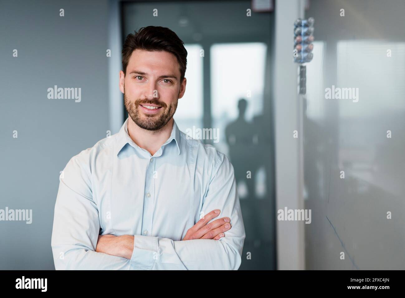 Mid adult male professional with arms crossed at work place Stock Photo ...