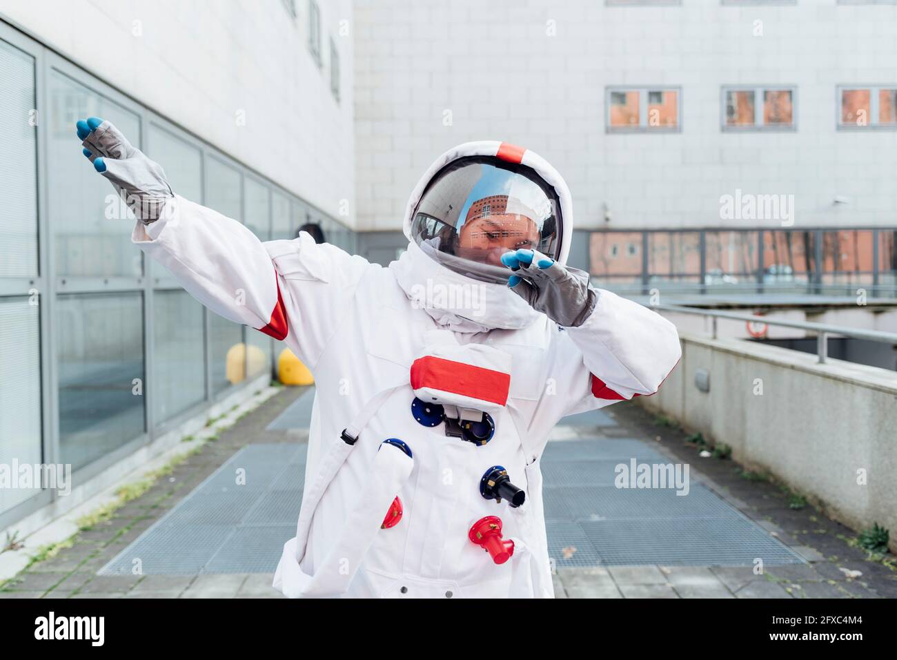 Female astronaut in space suit doing dab while standing near building ...