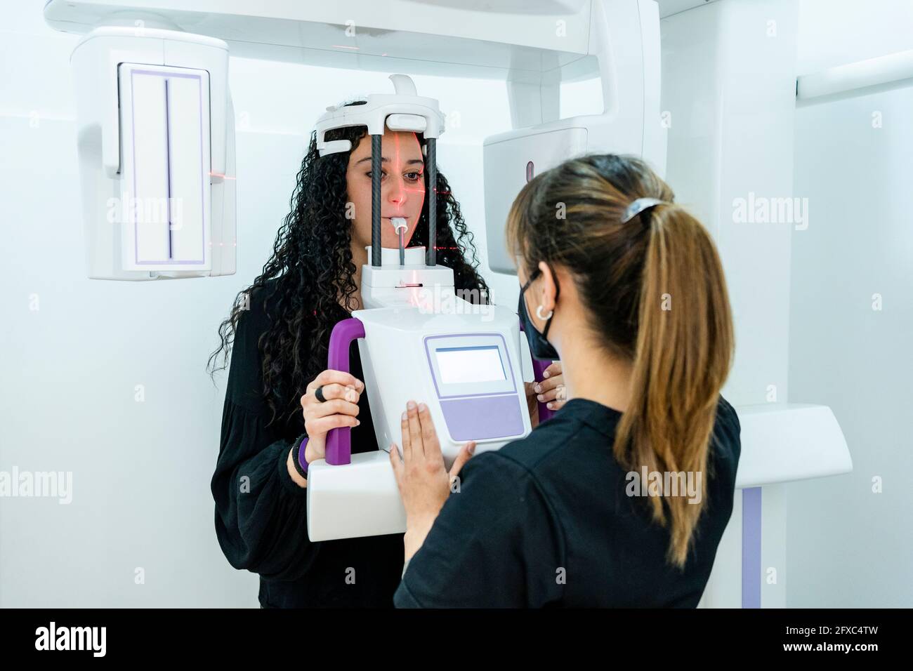 Female dentist operating machine during medical examination of young ...