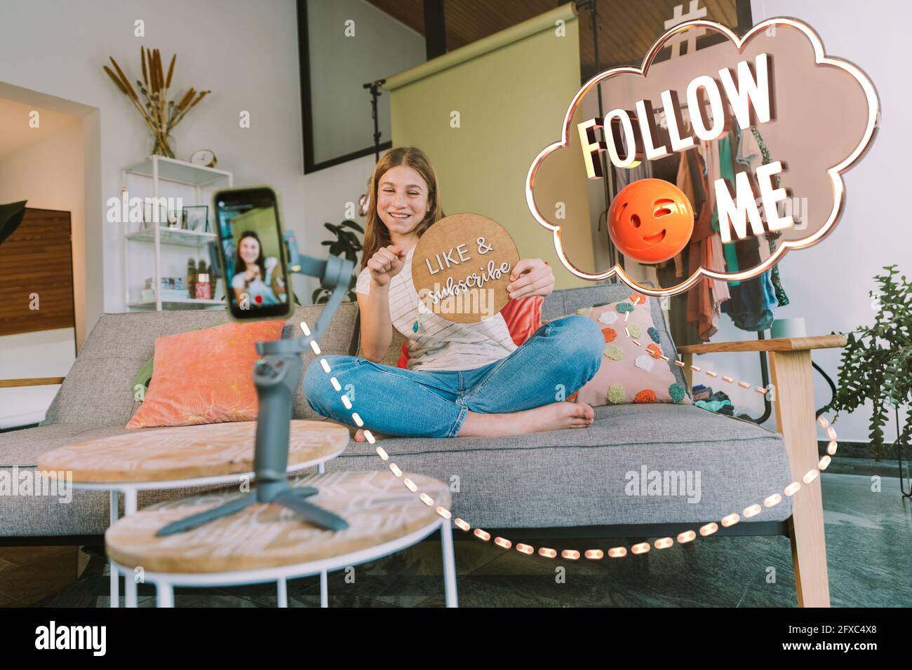 Smiling female influencer with like and subscribe cardboard vlogging ...