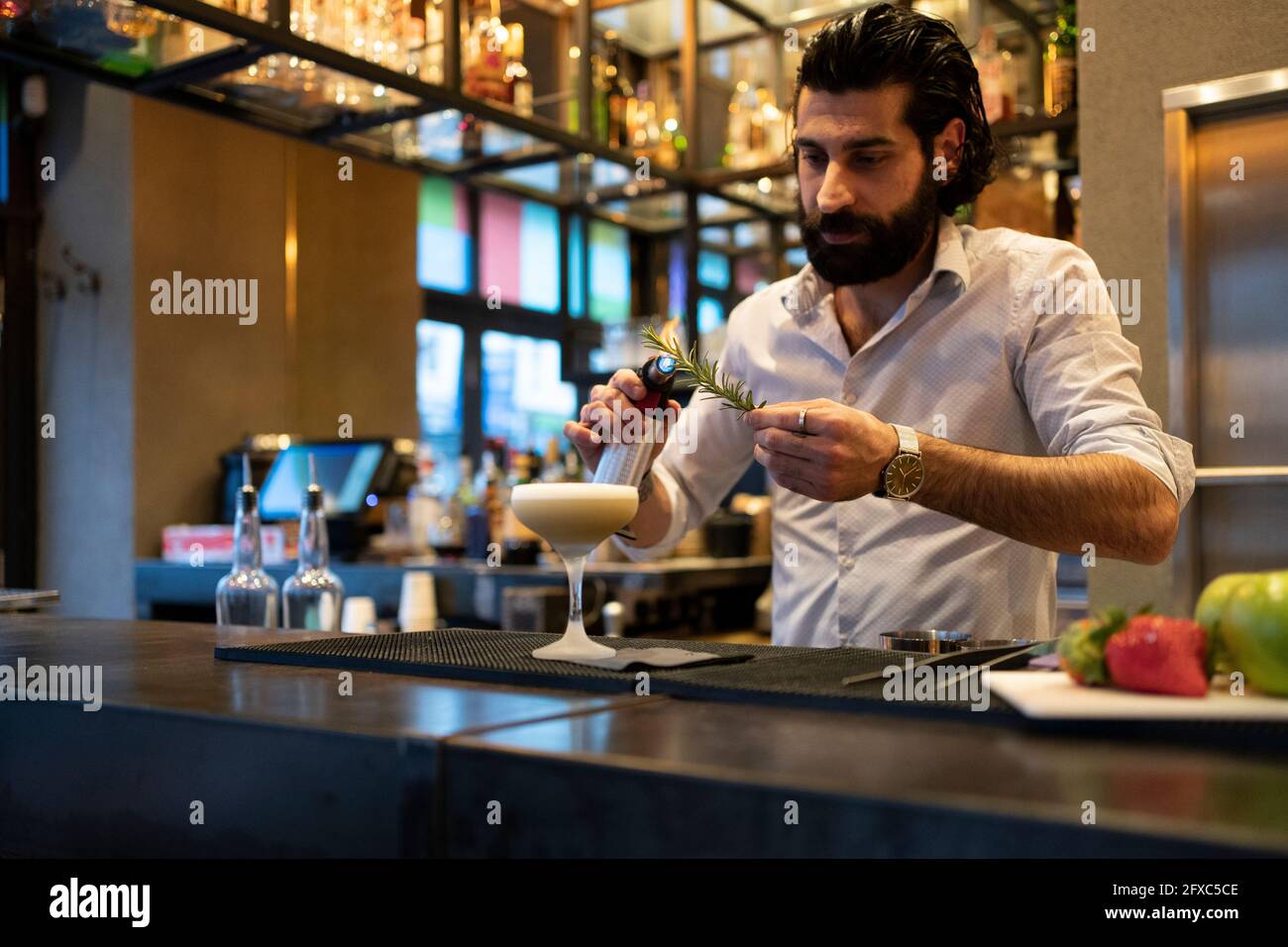 Bartender burning thyme with blow torch at bar counter Stock Photo - Alamy