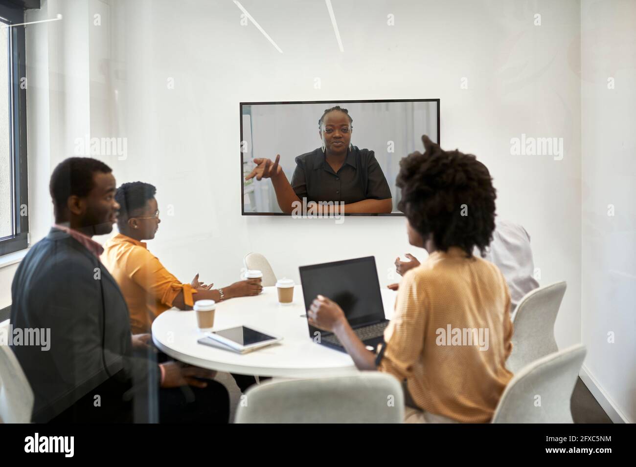 Female professional discussing with coworkers during video conference ...