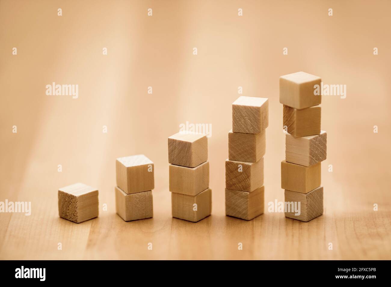 Rising small wooden square blocks on wooden background Stock Photo - Alamy