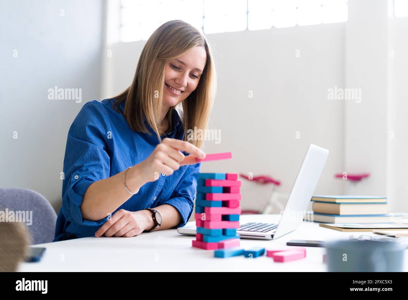 Smiling businesswoman playing block removal game at office Stock Photo ...
