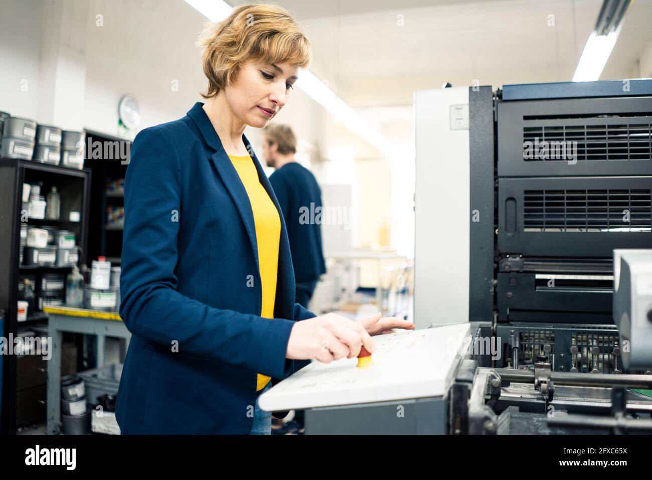 Female engineer using printing machine while working with colleague in ...