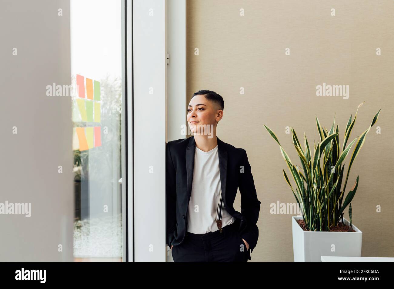 Thoughtful entrepreneur looking through window in office Stock Photo ...