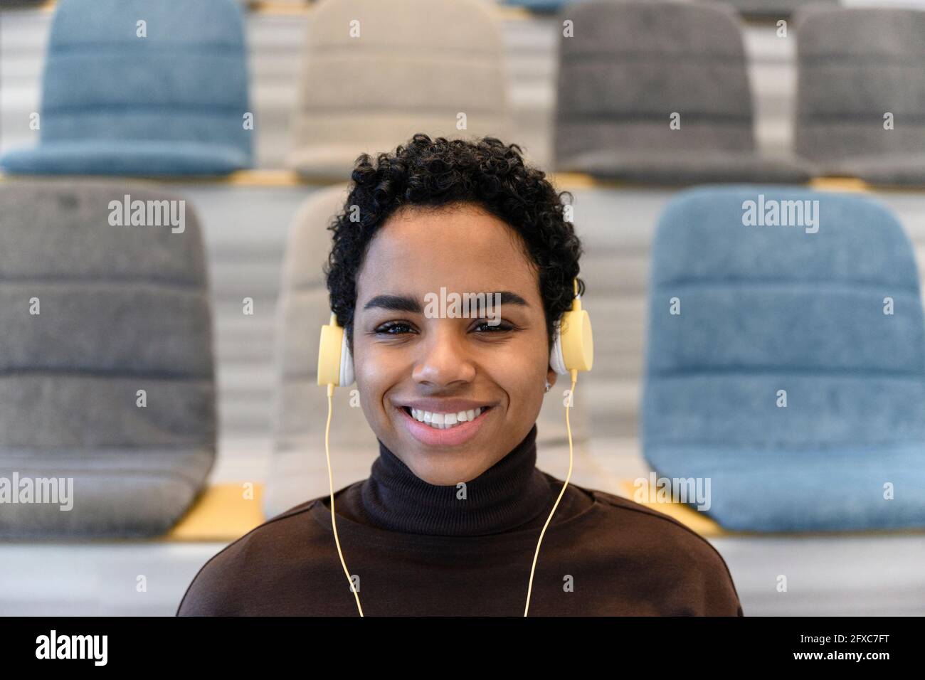 Cheerful woman wearing headphones at auditorium Stock Photo - Alamy