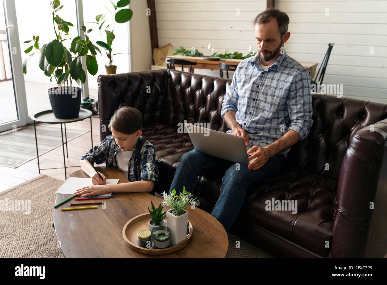 Father using laptop while son drawing at home Stock Photo - Alamy