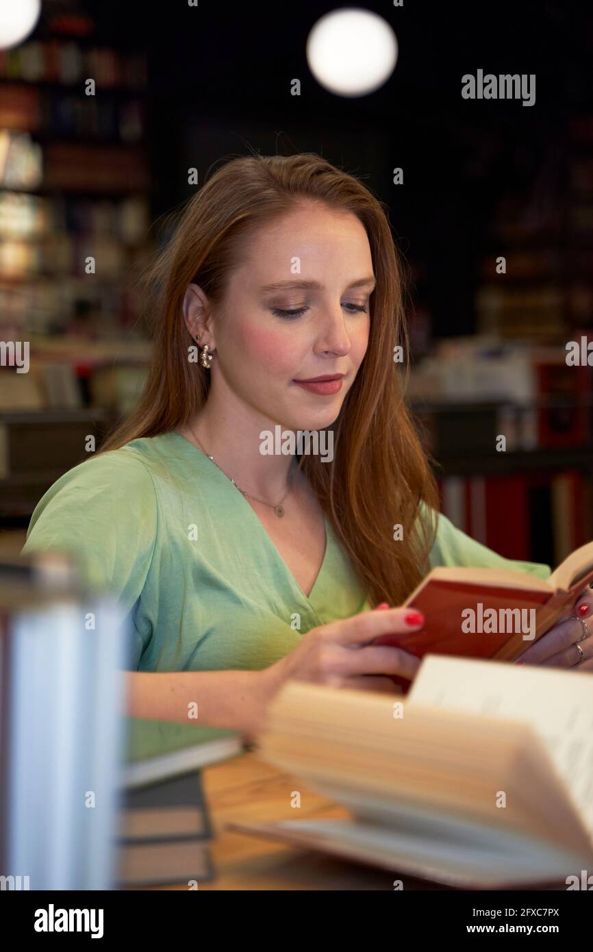 Young woman concentrating while reading book in library Stock Photo - Alamy
