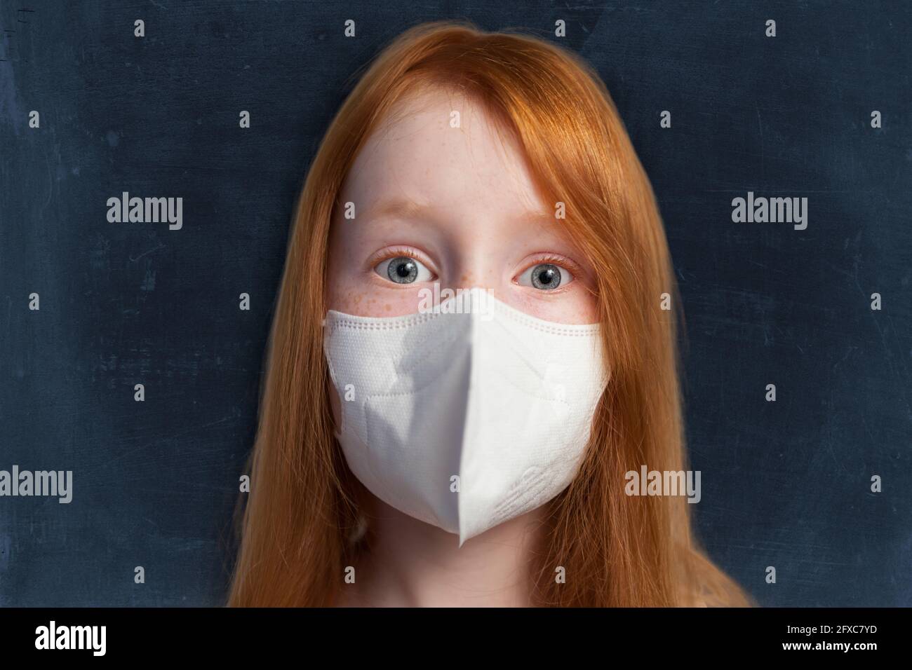 Redhead girl wearing protective face mask against black background ...