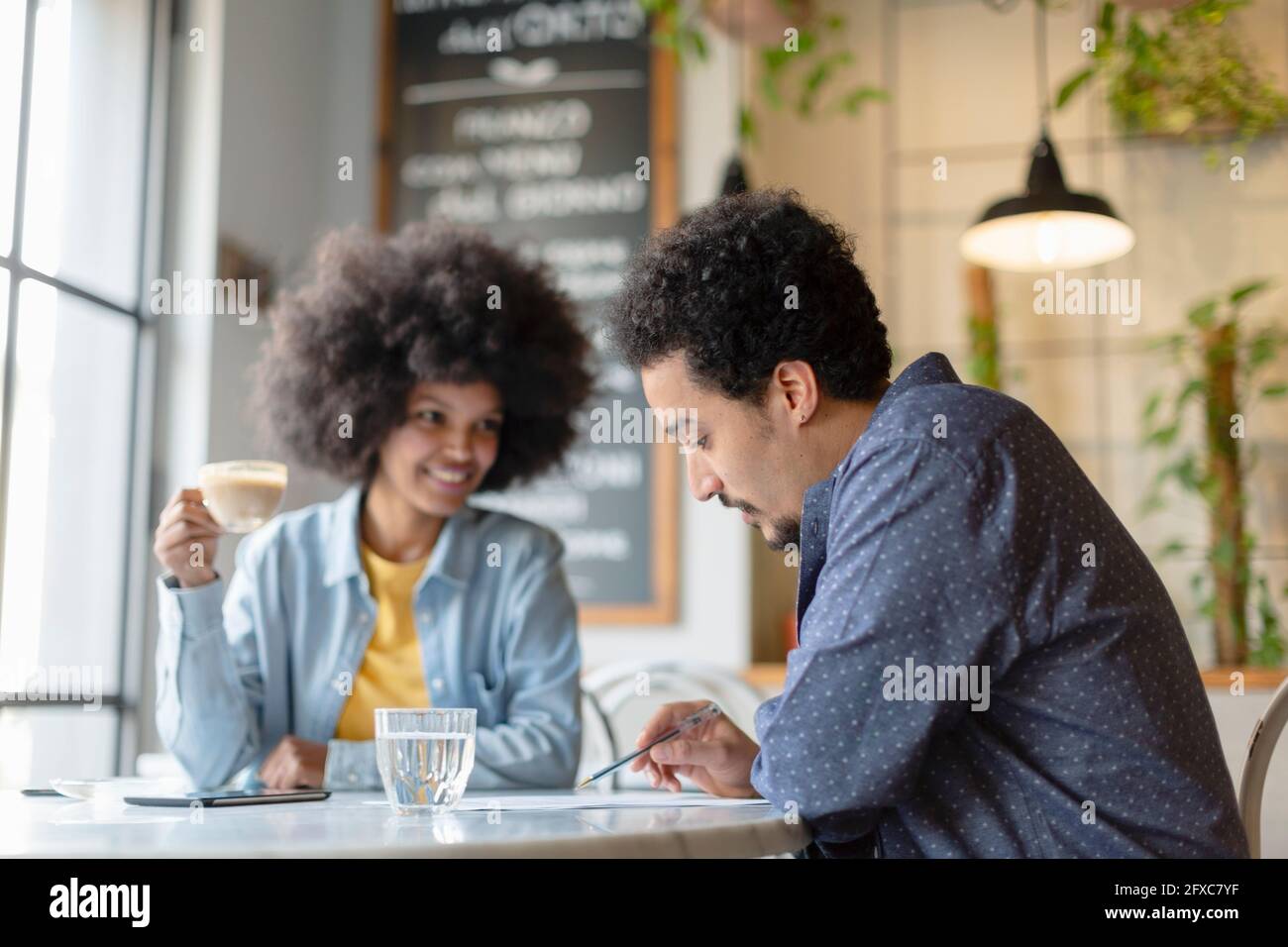 Male customer reading contract while sitting with female entrepreneur ...