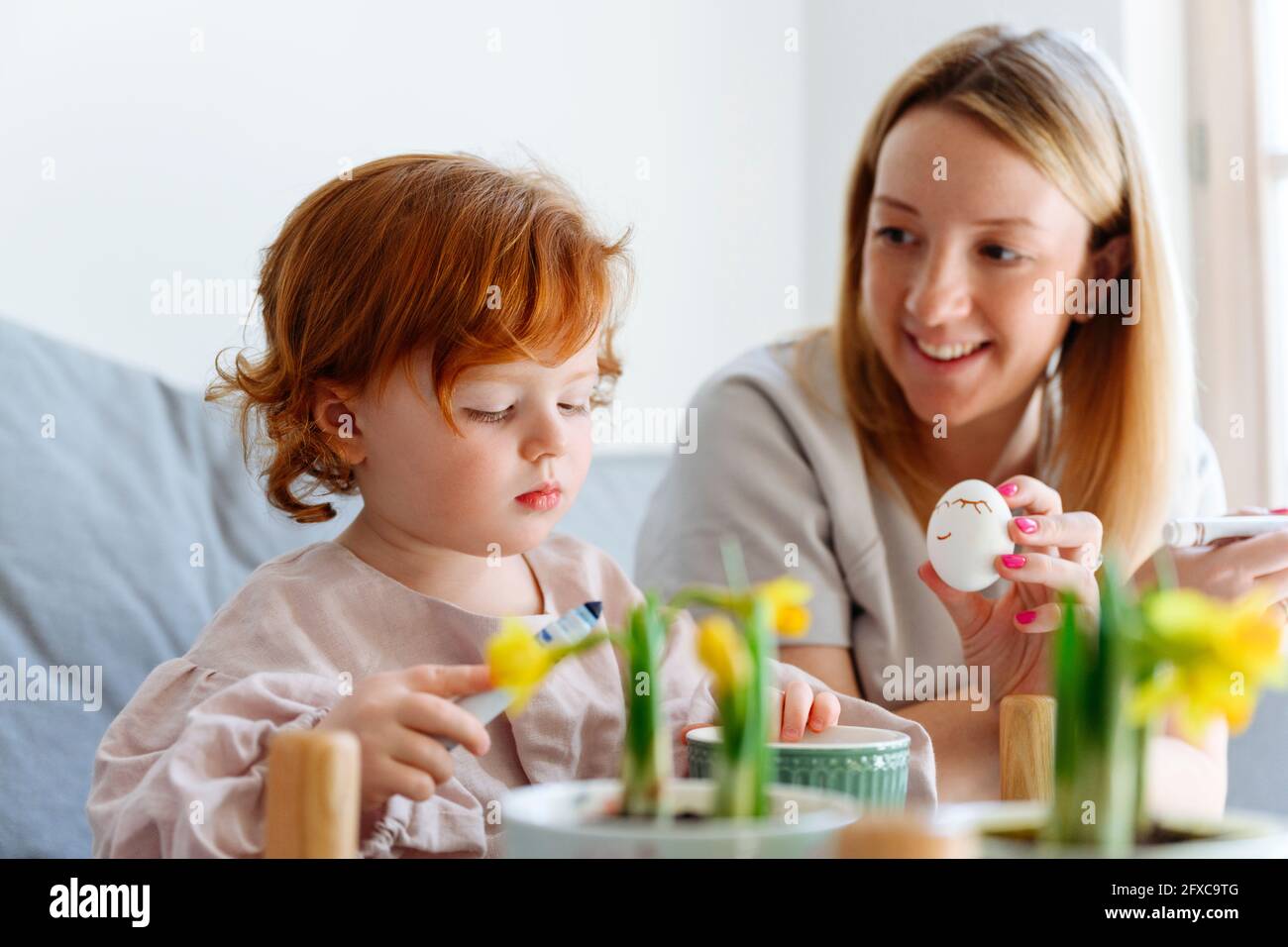 Smiling mother showing Easter egg to daughter at home Stock Photo - Alamy