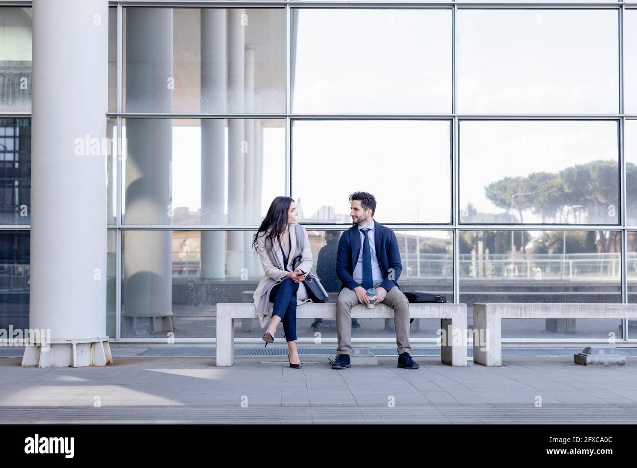 Business couple talking while sitting on bench Stock Photo - Alamy