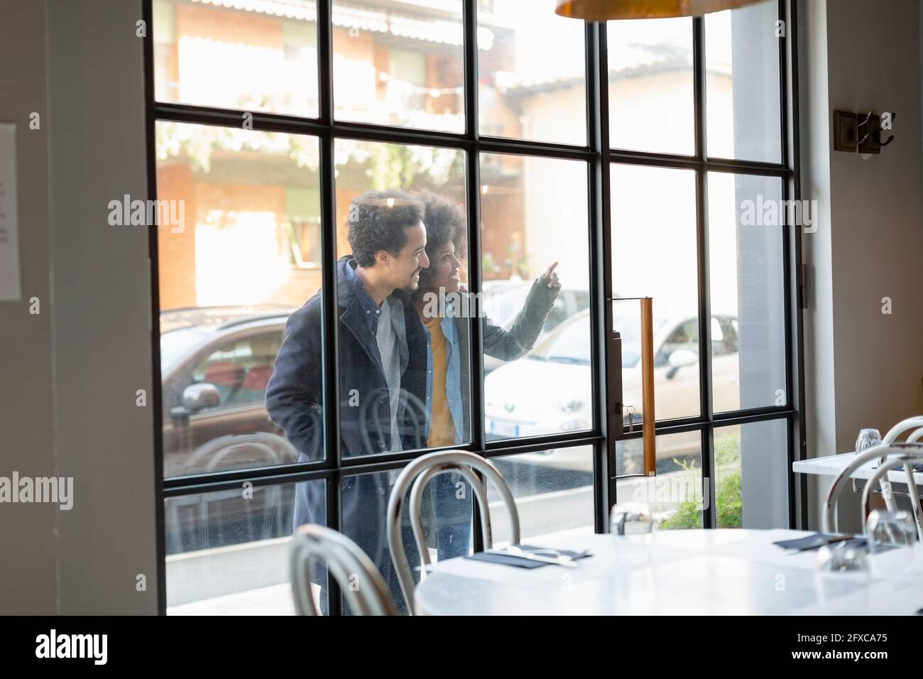 Boyfriend and girlfriend looking through window while standing outside ...