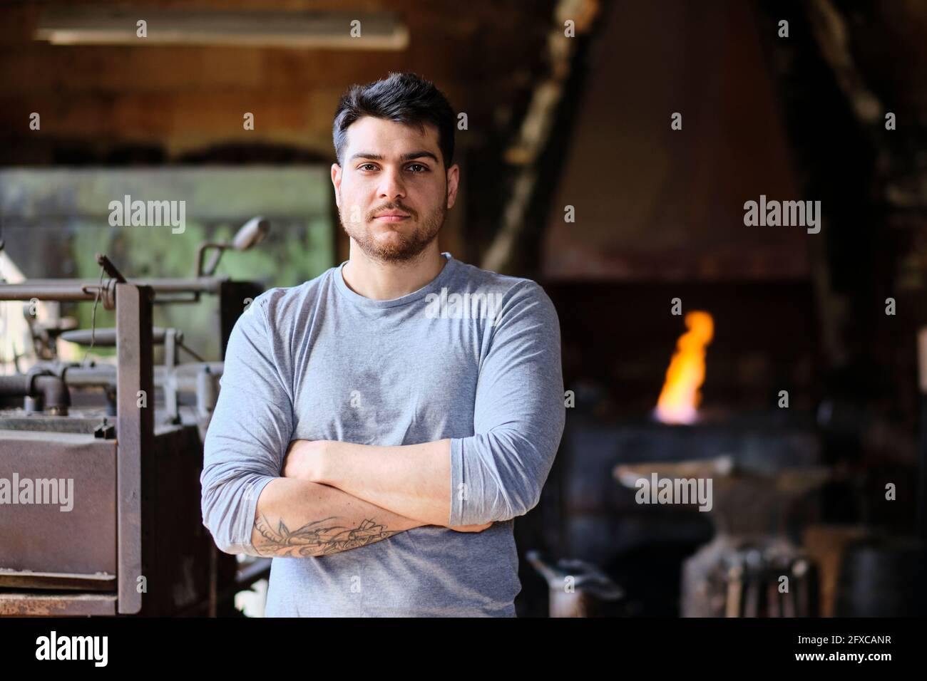 Confident male blacksmith standing with arms crossed at workshop Stock ...