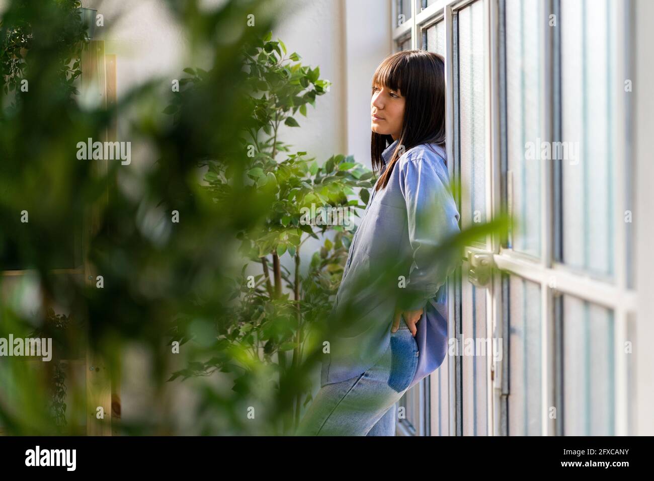Thoughtful woman leaning on window at home Stock Photo - Alamy