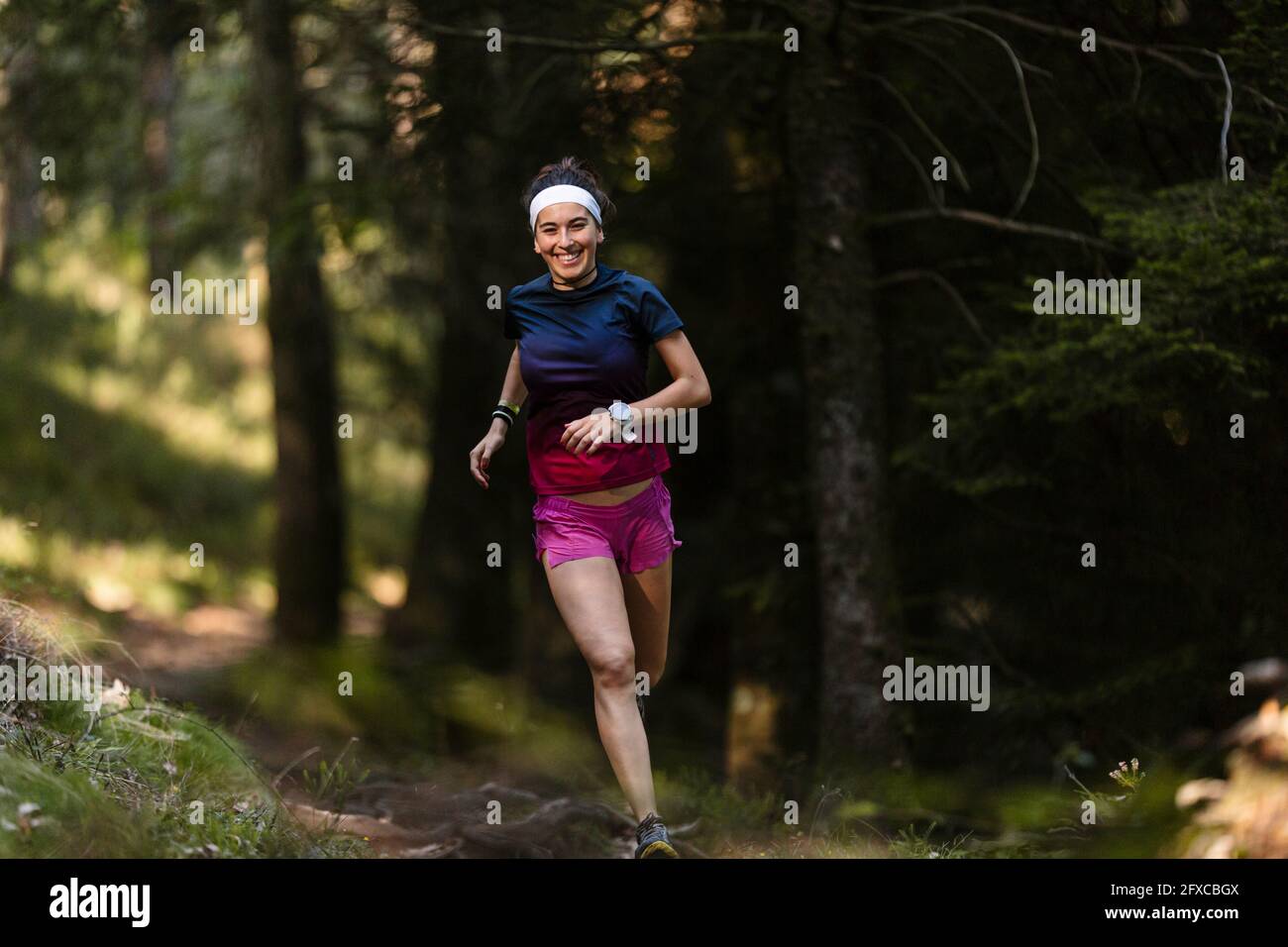 Happy young female sportsperson running in forest Stock Photo - Alamy