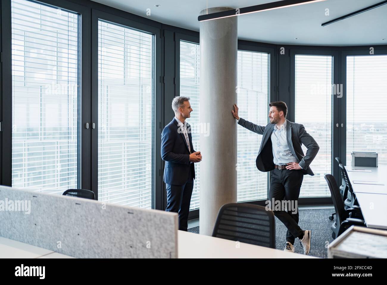 Business people talking while standing by architectural column in ...