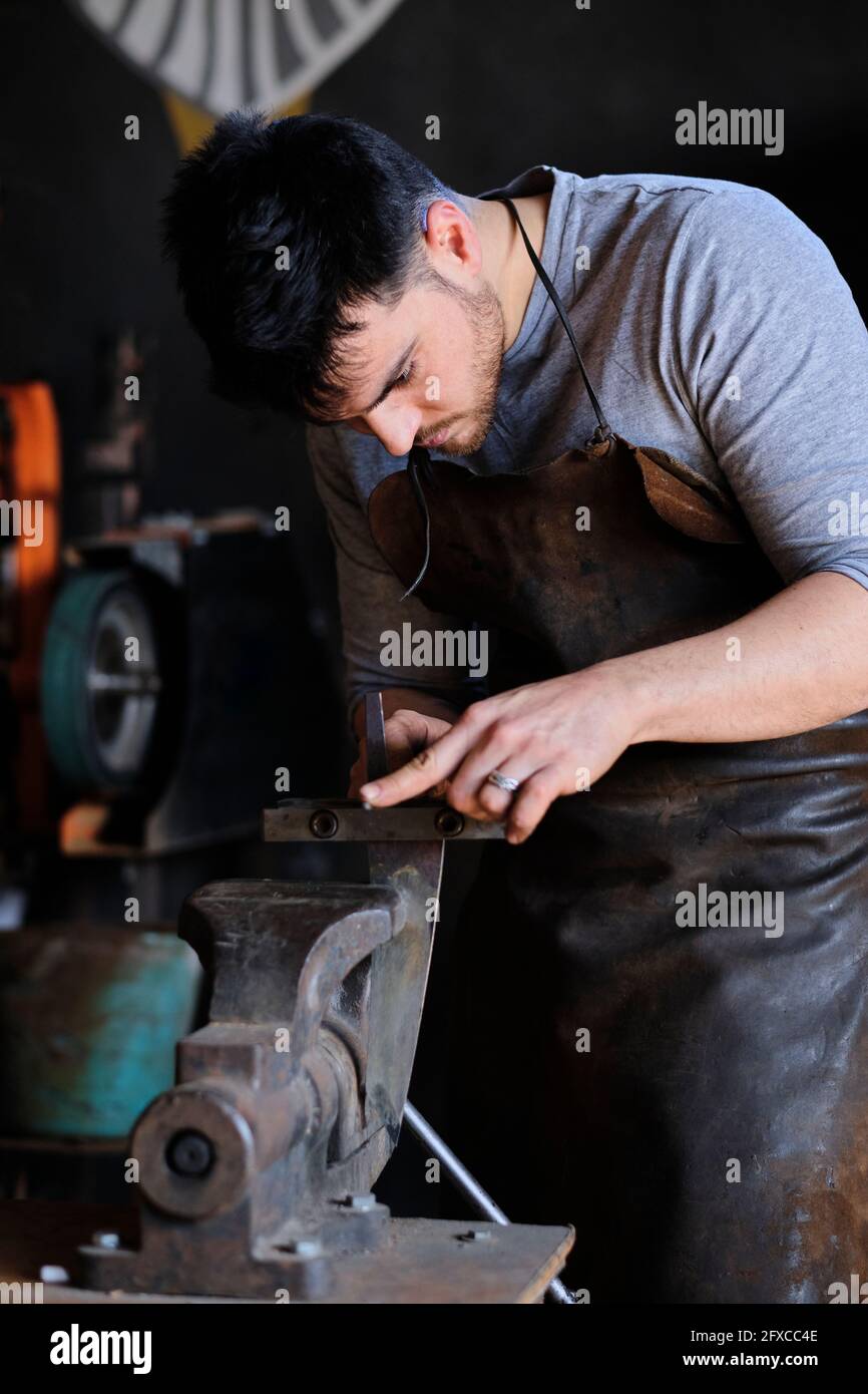 Young male blacksmith working on machine at workshop Stock Photo - Alamy