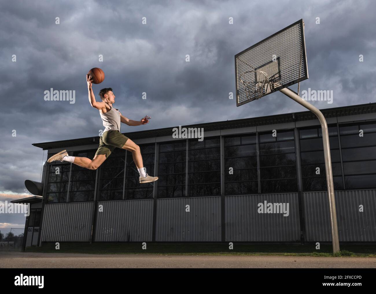 Young man jumping while playing basketball Stock Photo - Alamy