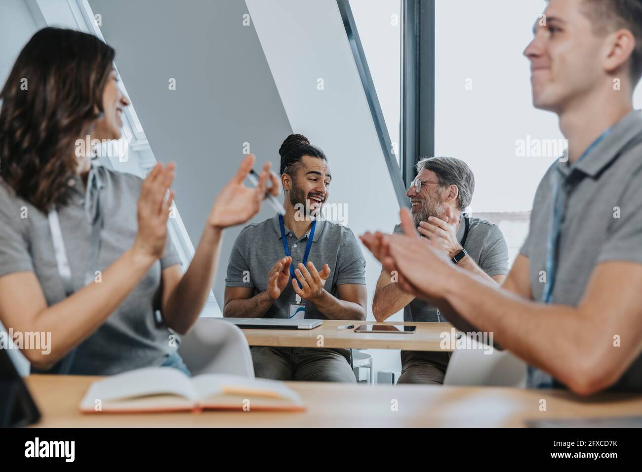 Male and female trainees clapping while sitting on bench in training ...