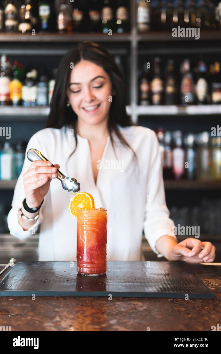 Smiling female bartender serving cocktail at counter Stock Photo - Alamy