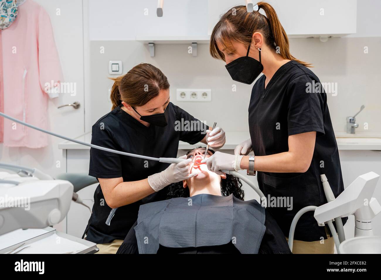 Female dentists cleaning teeth of patient at medical clinic Stock Photo - Alamy