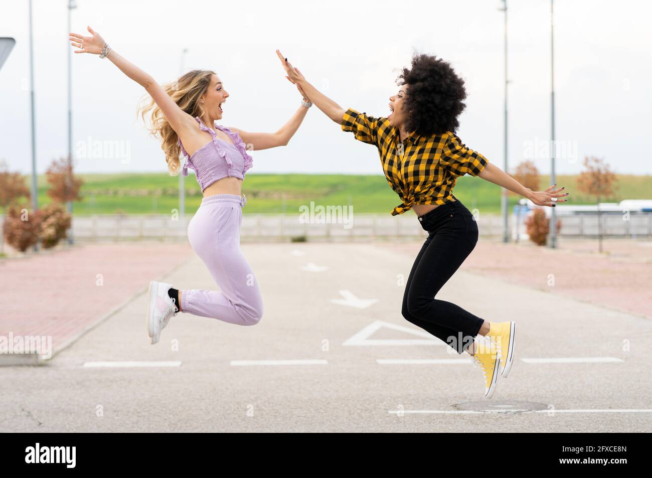 Female friends jumping on road outdoors Stock Photo - Alamy