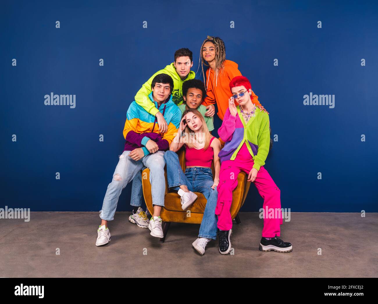 Young friends sitting together on armchair at studio Stock Photo - Alamy