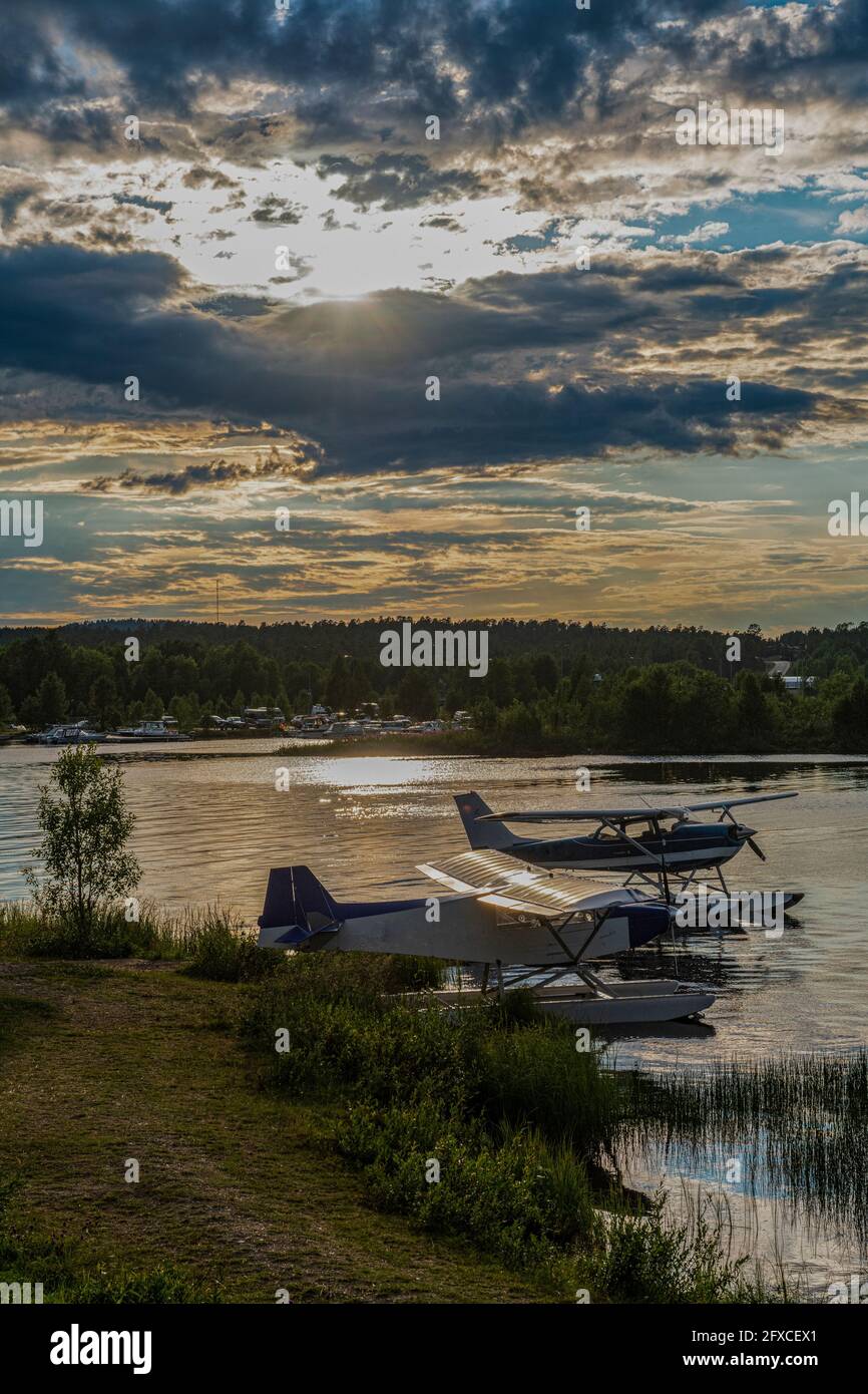 Finland, Lapland, Inari, Dramatic sunset over seaplanes left on shore ...