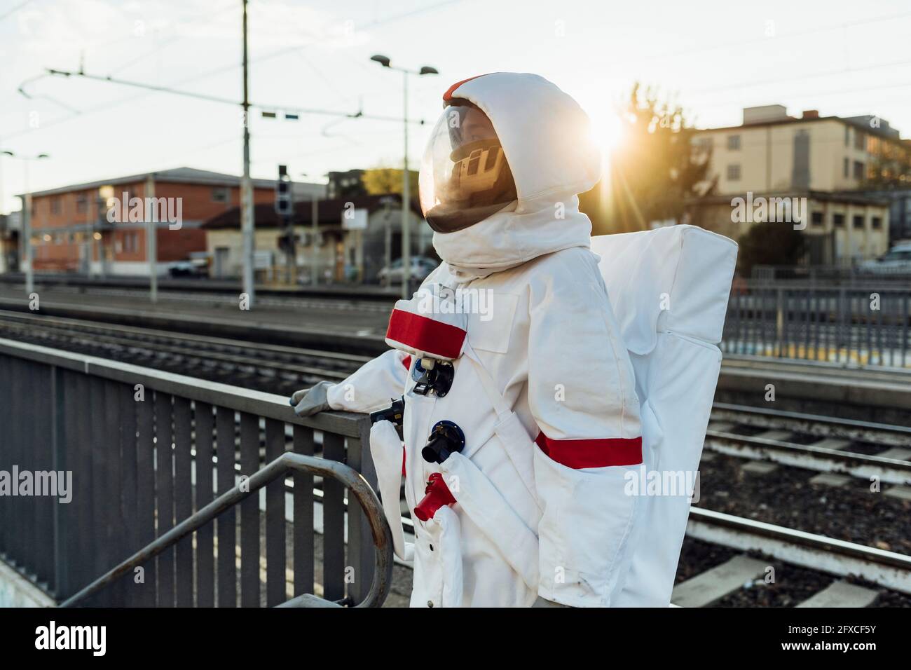 Female astronaut looking away while standing near railing at station ...